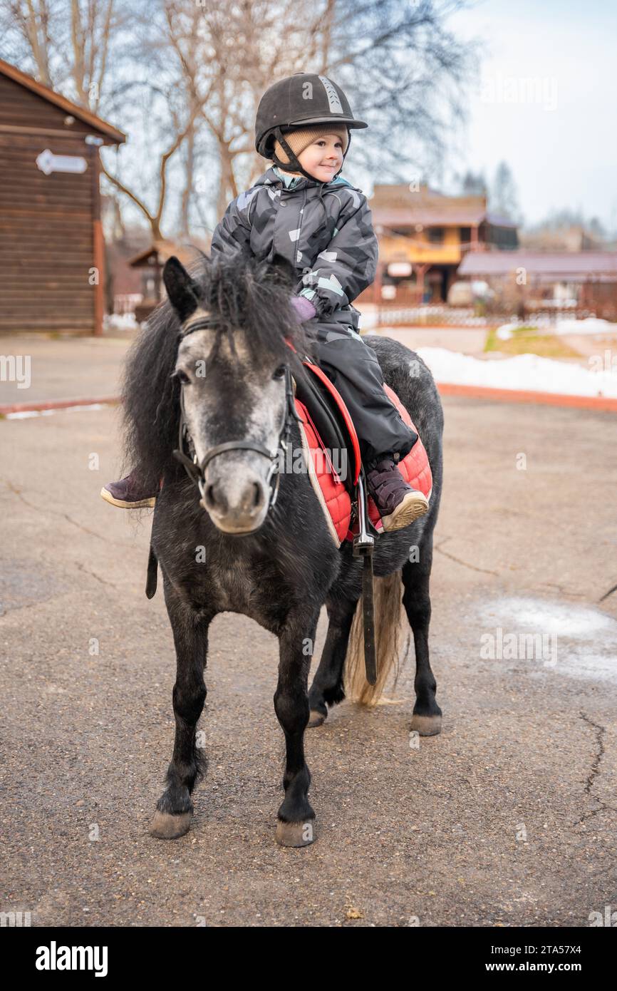 Cute little girl riding a little horse or pony in winter on farm Stock ...