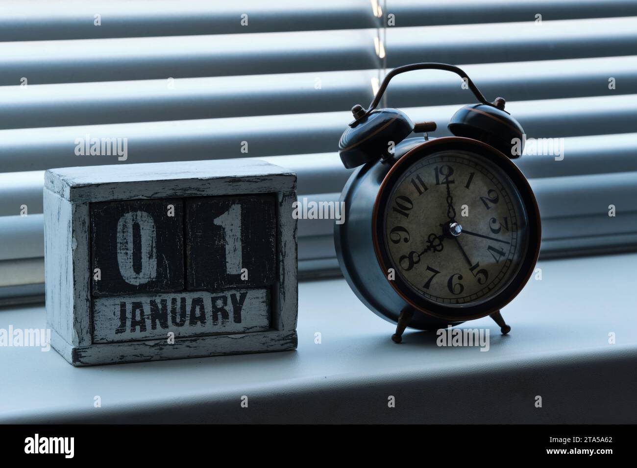 Morning of January 01 on wooden calendar standing window with blinds ...