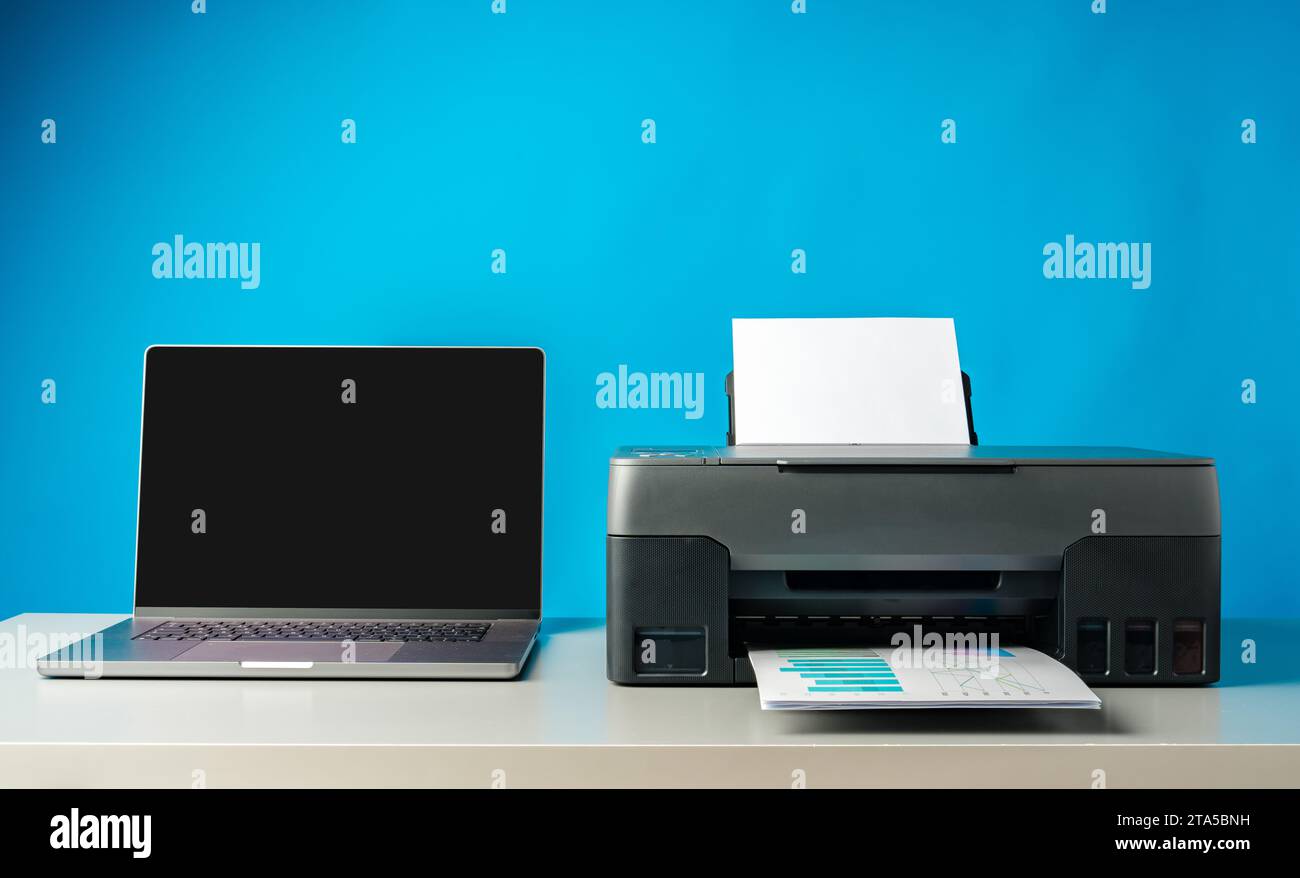 Modern printer with paper and laptop on table in office Stock Photo - Alamy