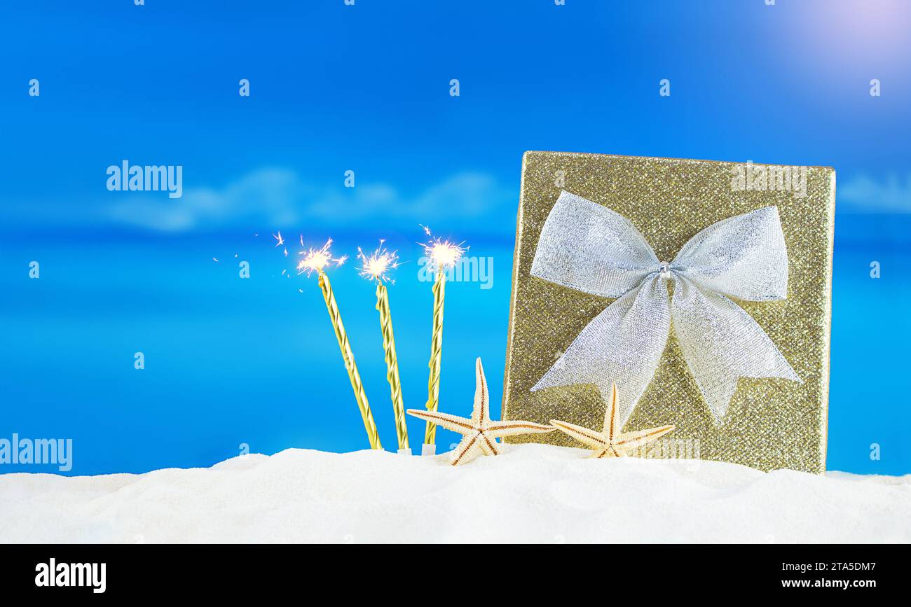 Golden shiny box with silver bow, candles with flames and starfish on ...