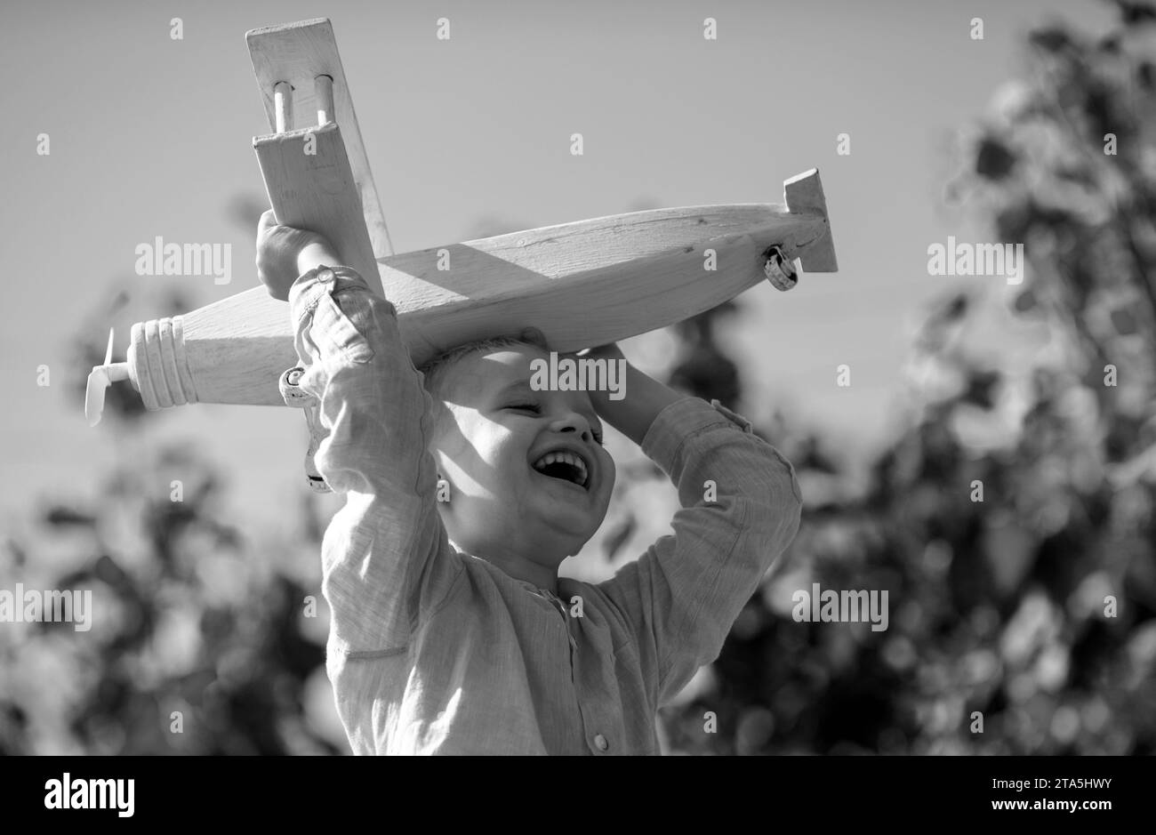 Kid dreaming and plays with a toy plane in the park. Dreams of travel ...