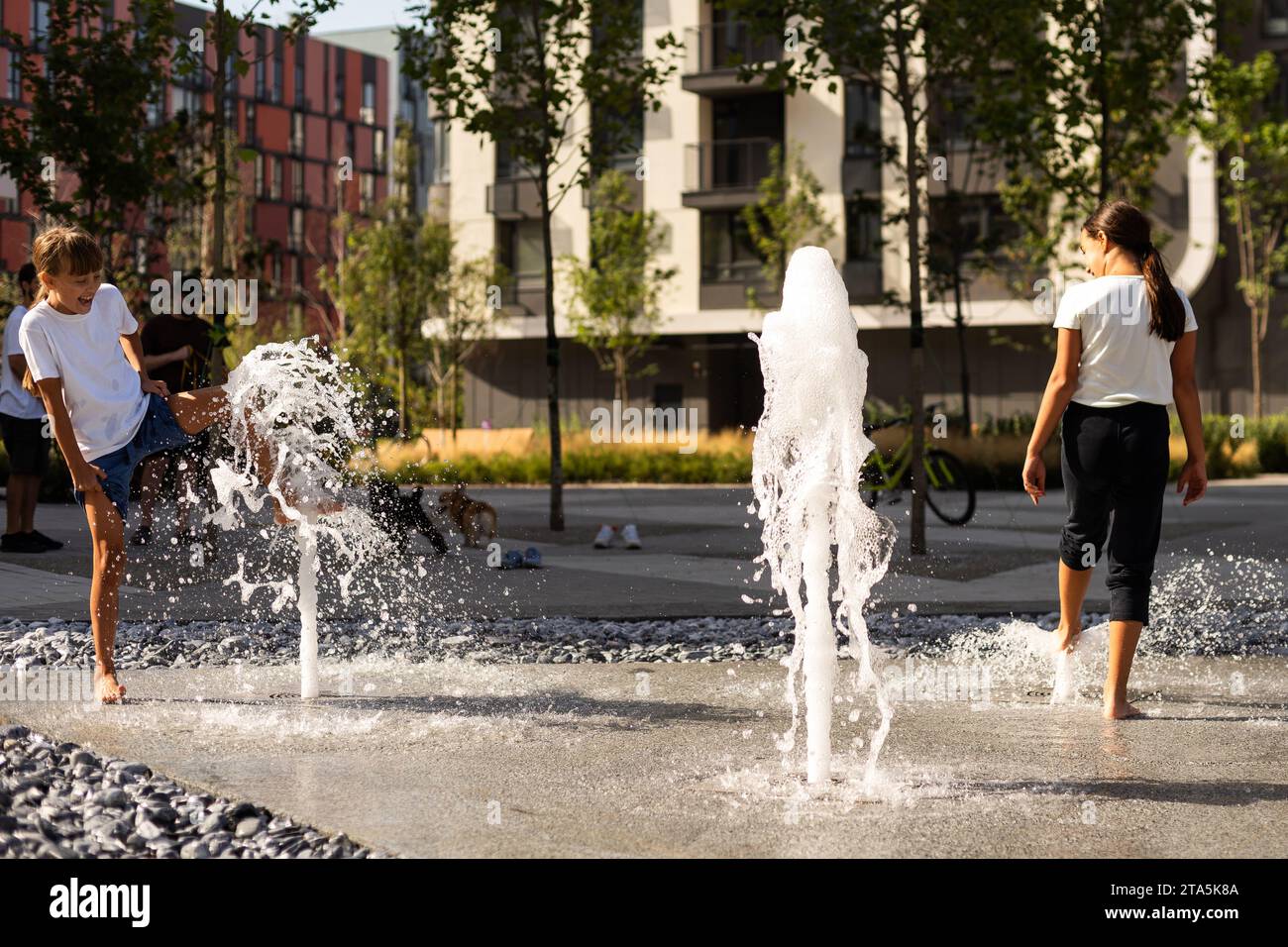 Cheerful young teen girl in city fountain, girl in wet clothes is ...