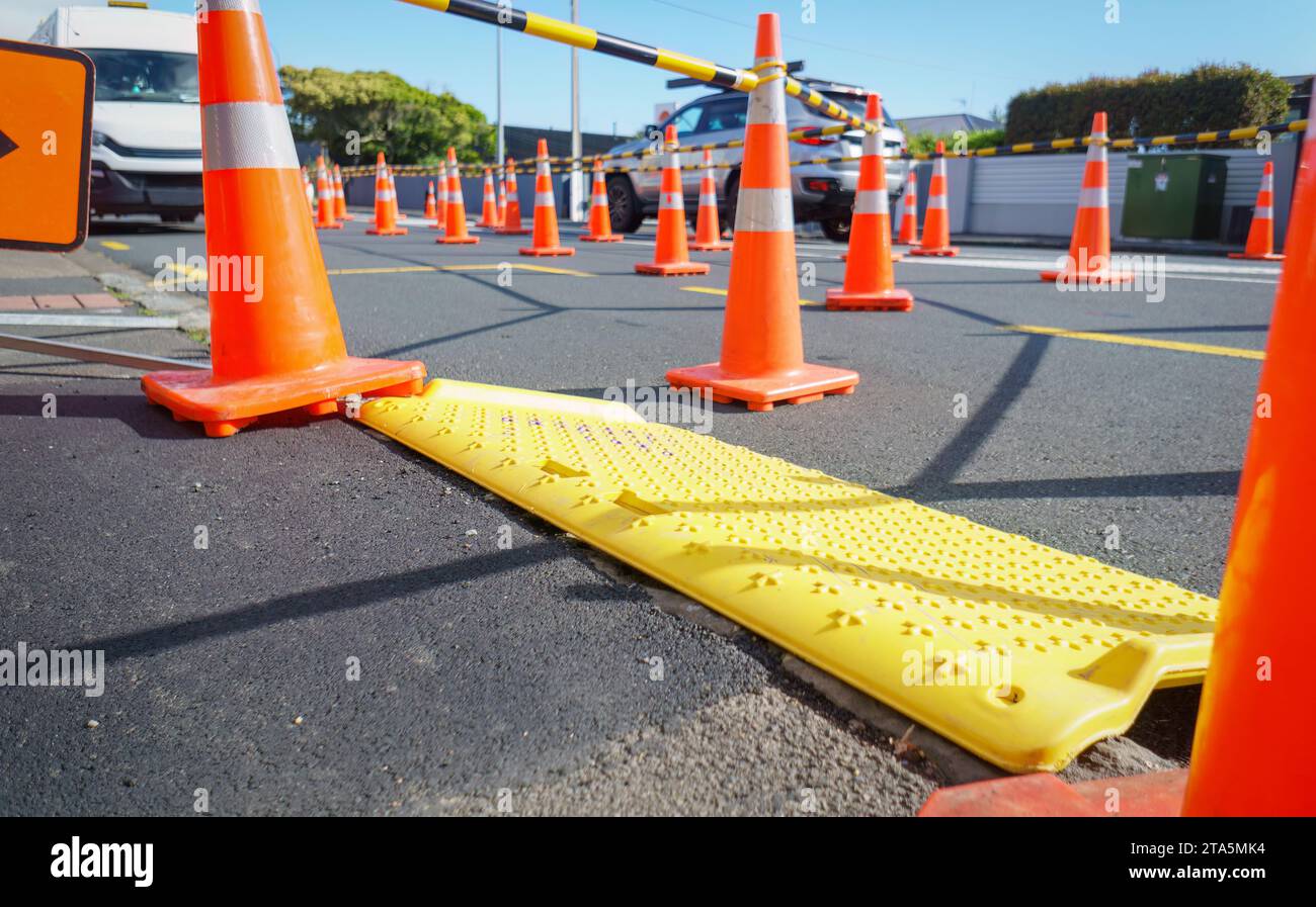Yellow road safety trench cover and orange traffic cones on the street ...