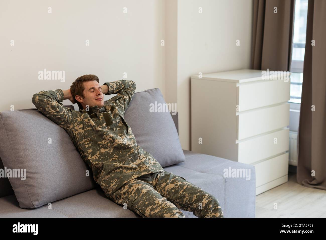 Soldier napping on soft sofa near TV in living room. Military service ...