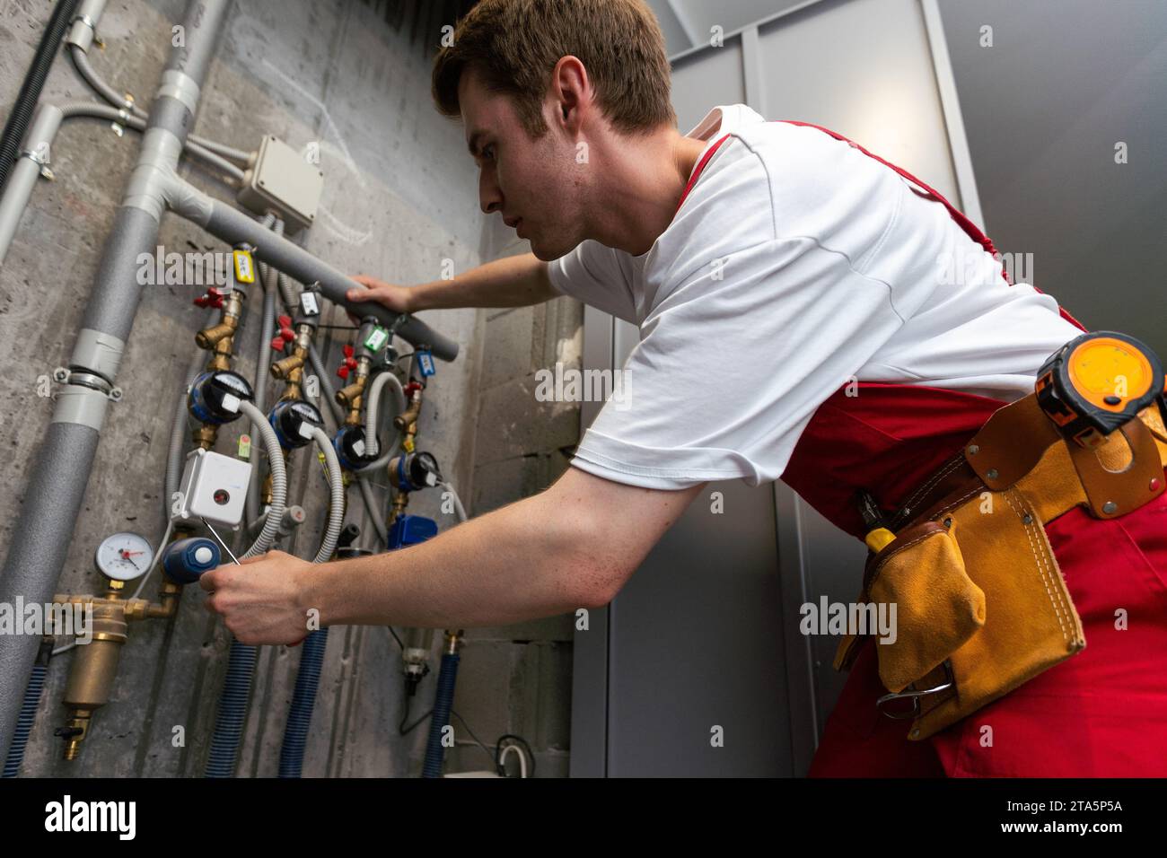 Male plumber fixing water meter with adjustable wrench Stock Photo - Alamy