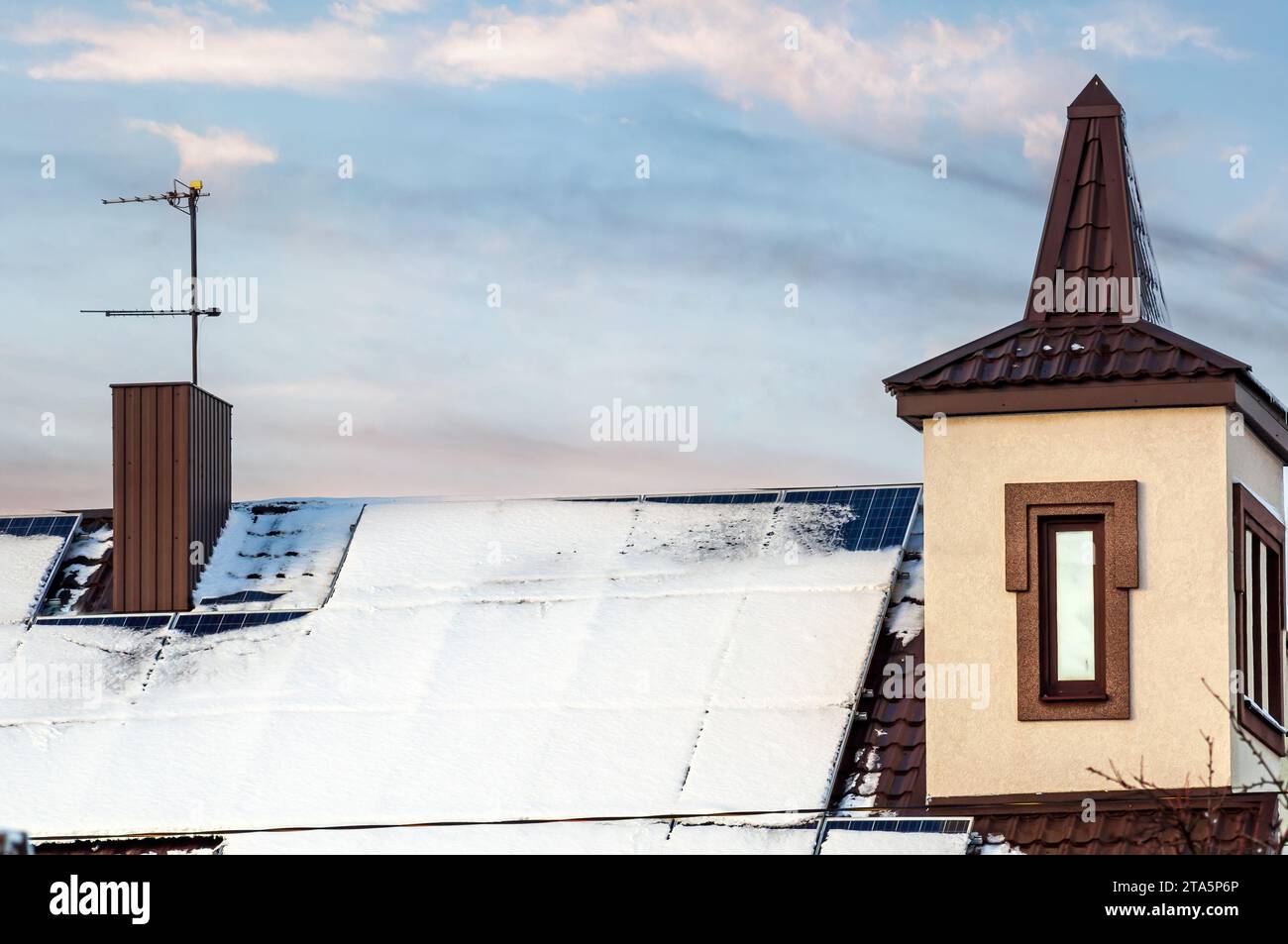 The roof of the house with mounted solar panel modules, winter snowy ...