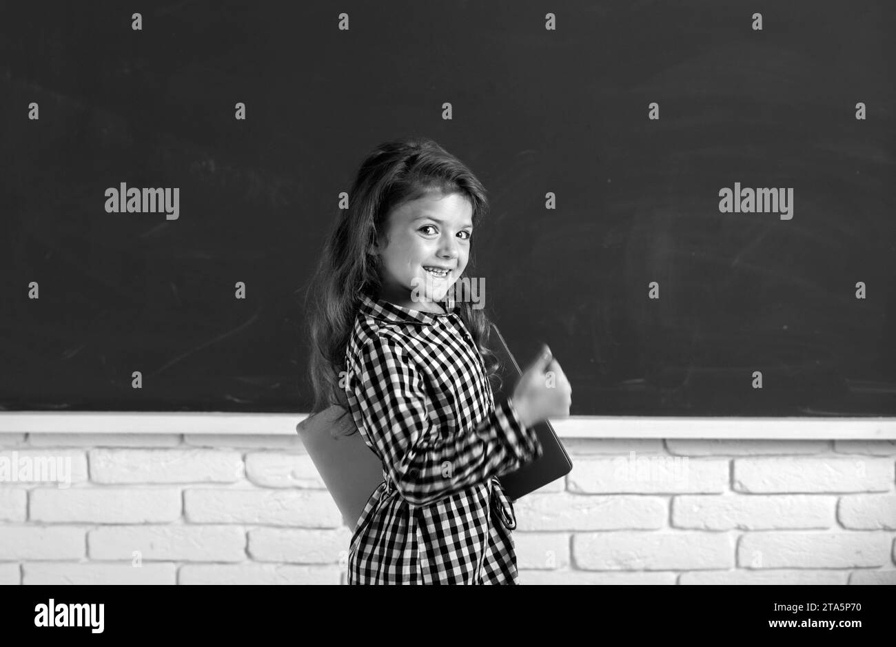 Portrait of funny pupil girl with laptop of primary school study ...