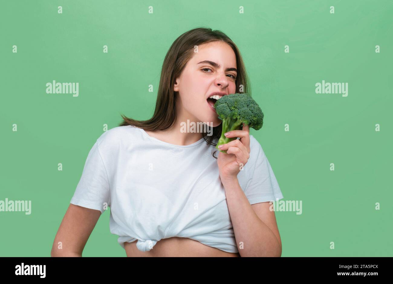 Portrait of happy funny young beautiful woman eating broccoli. Healthy ...