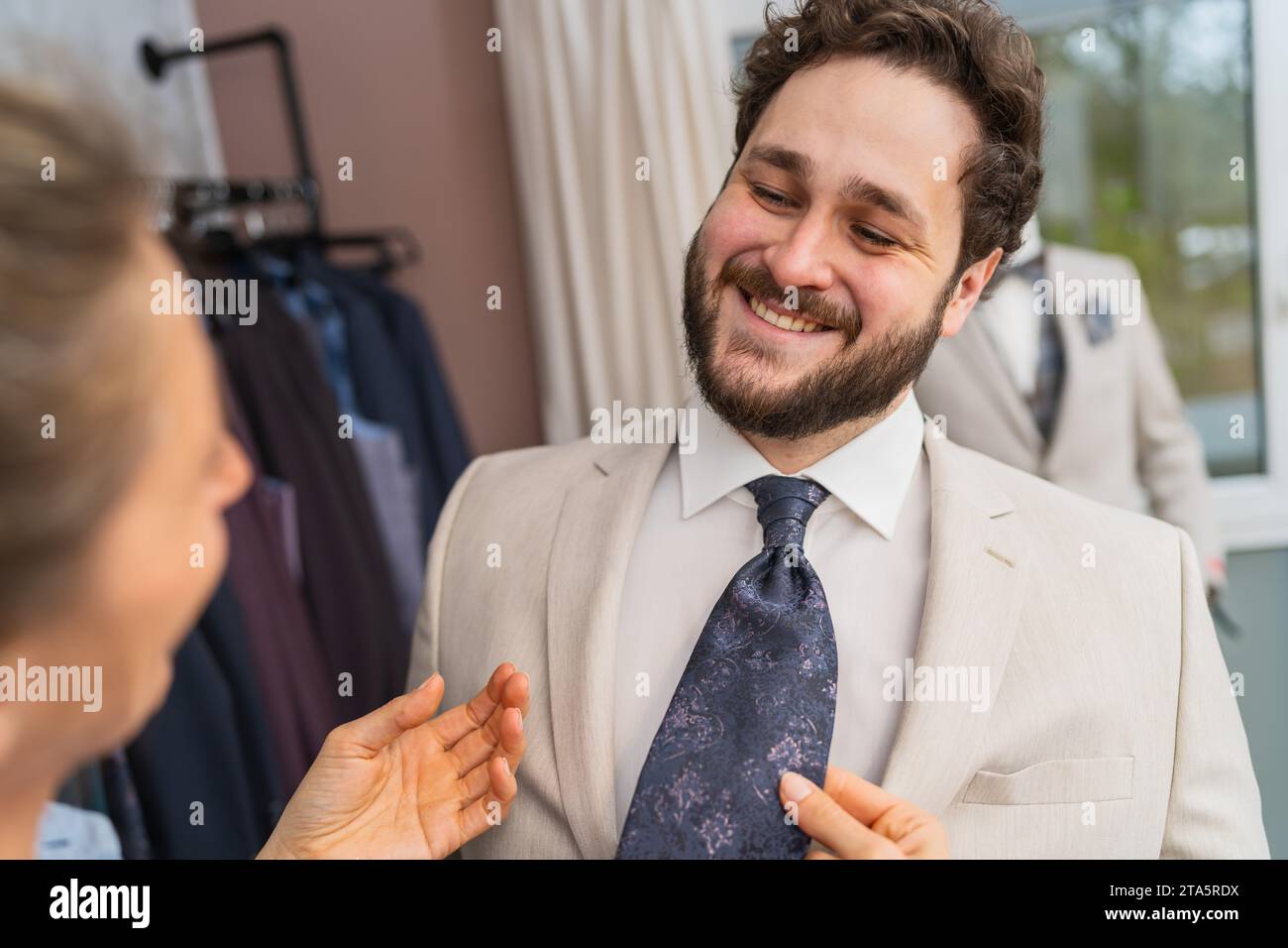Happy man in a suit being fitted for a tie by a tailor Stock Photo - Alamy