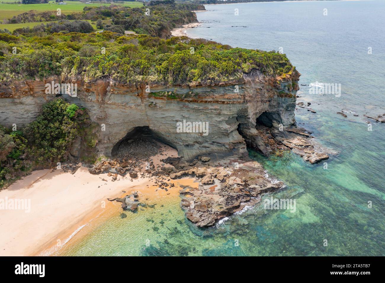 Aerial view of coastal caves in a rocky bluff jutting out into the sea ...
