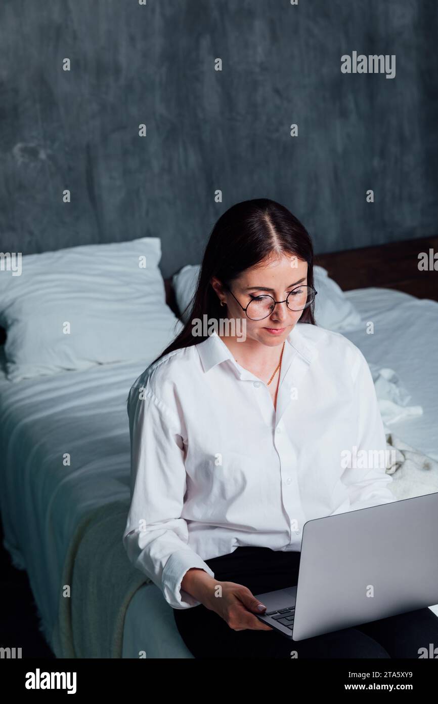 Business woman working at computer in bedroom on bed Stock Photo - Alamy