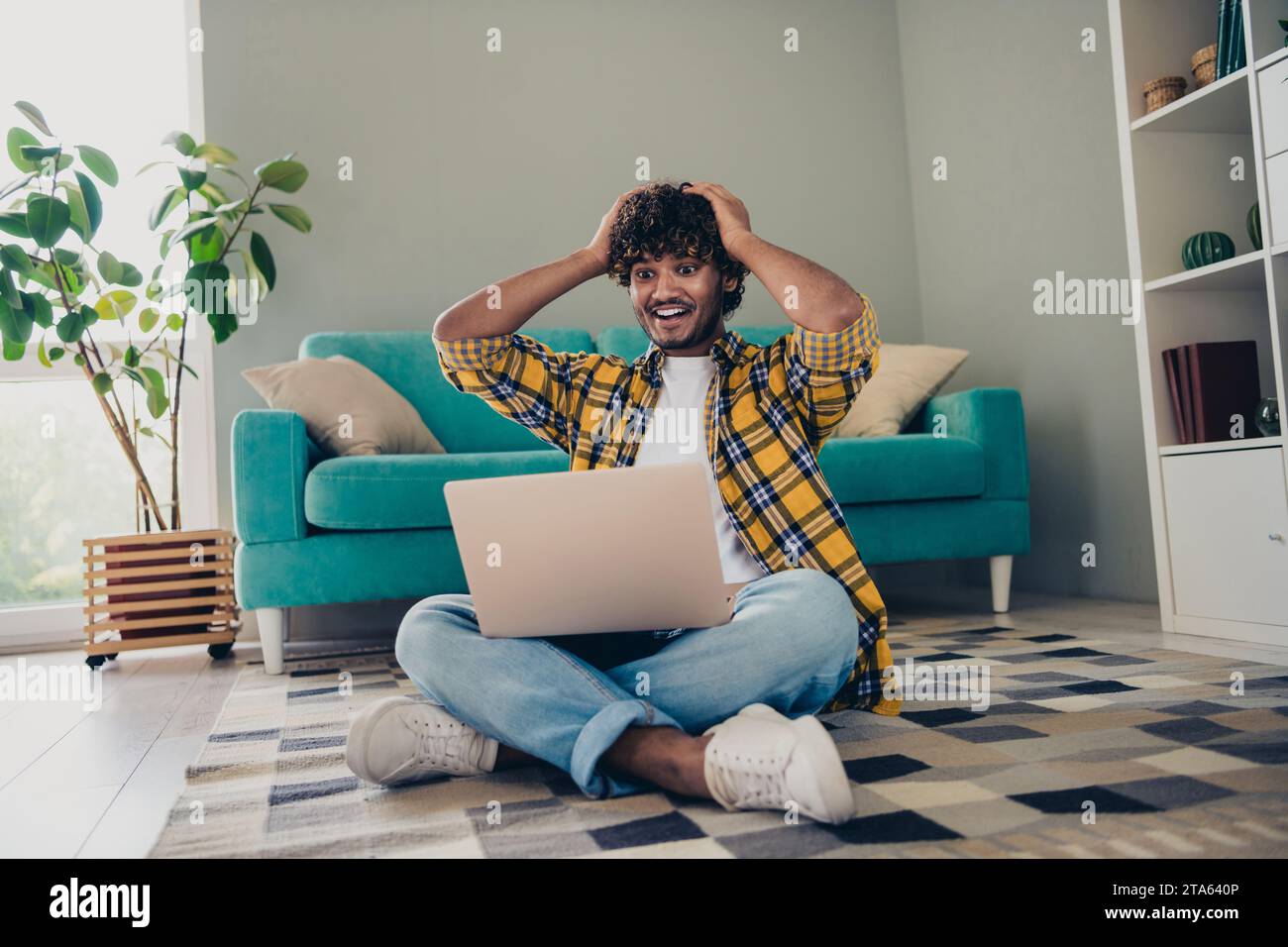 Photo of cheerful excited man sit on floor comfort room hands touch ...
