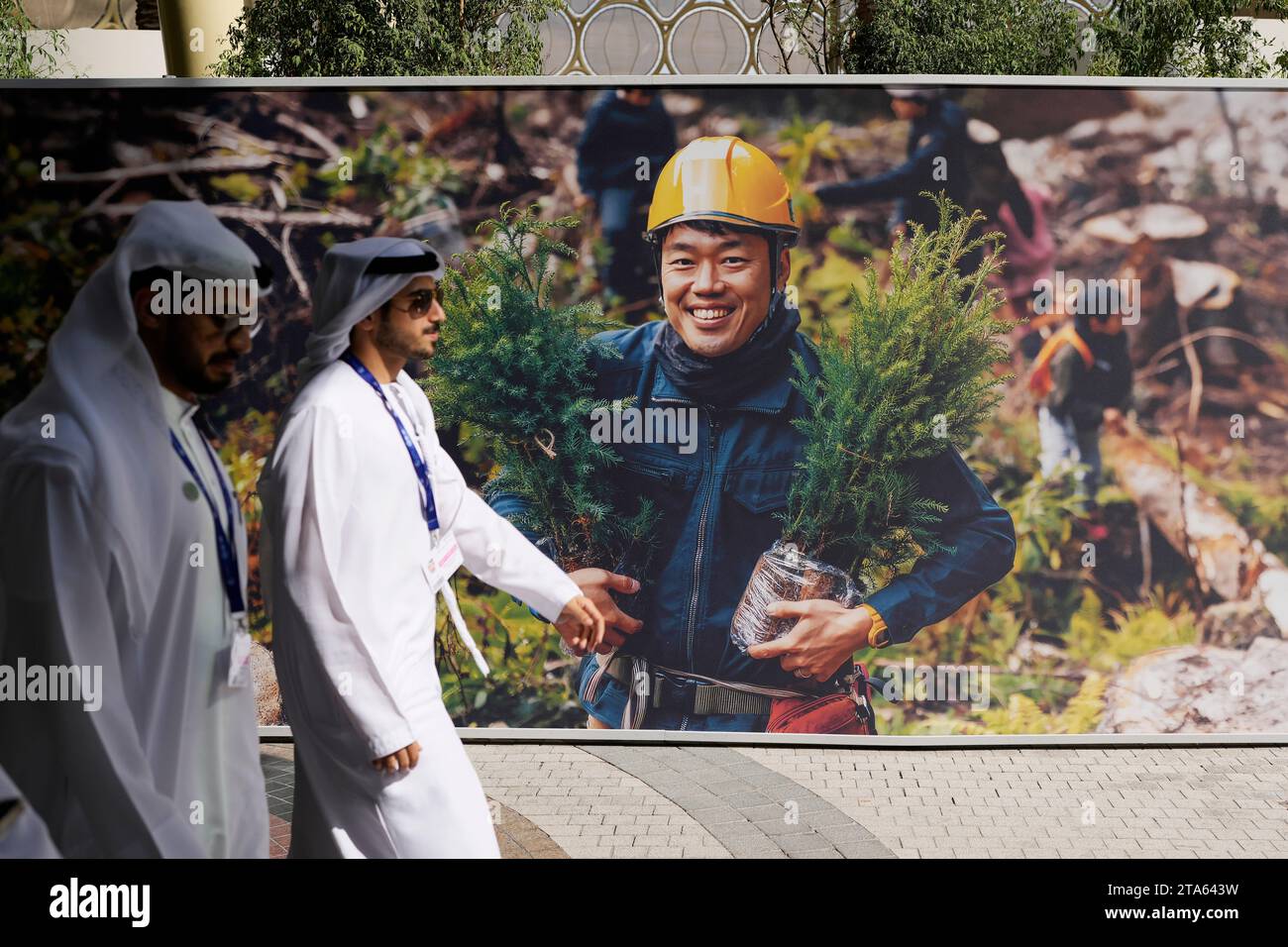 People walk past a poster ahead of the COP28 U.N. Climate Summit ...