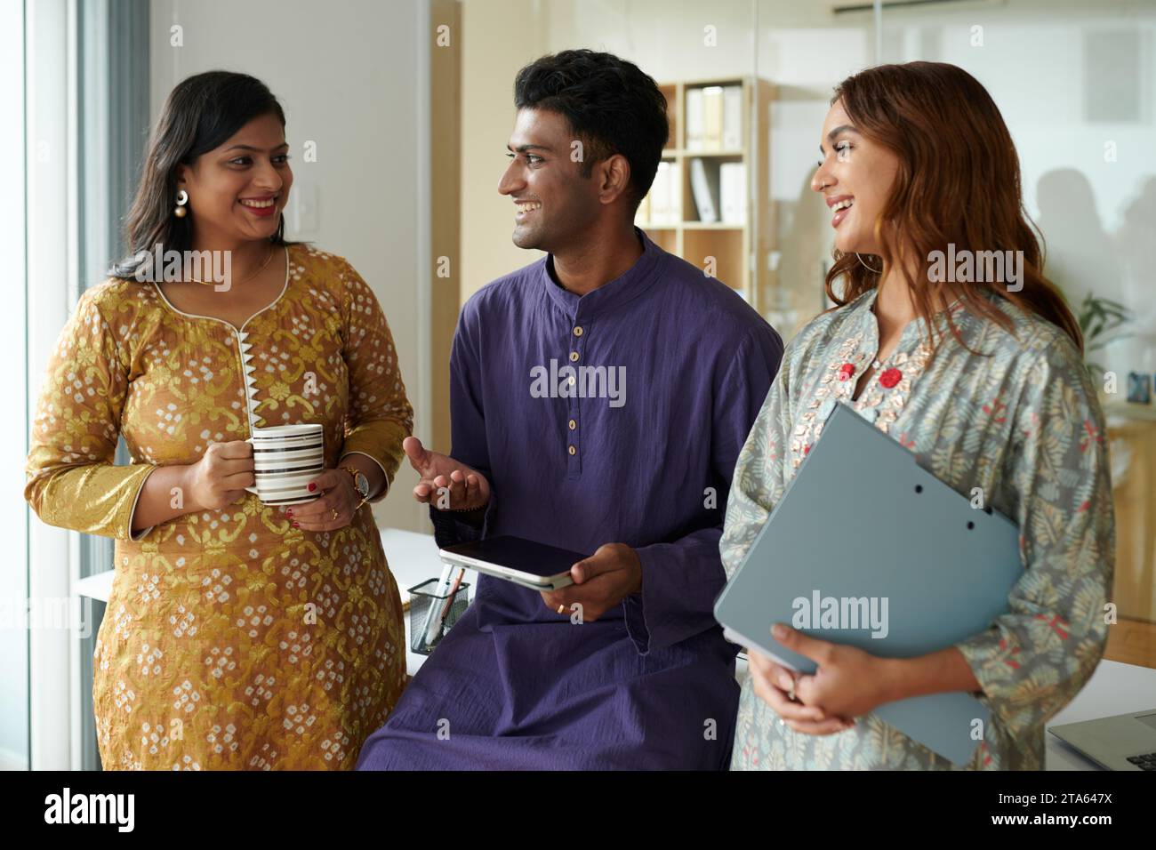 Smiling Indian business colleagues in traditional clothes discussing ...