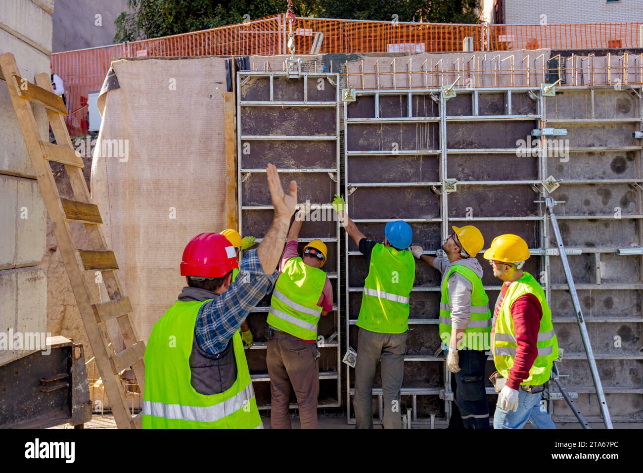 View from behind on worker as shows sing with hand to crane as team of ...