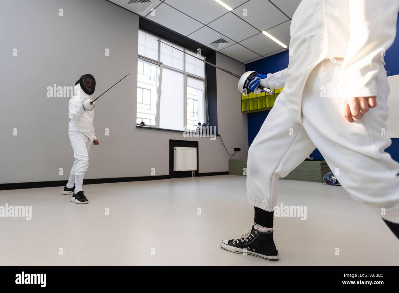 Adults and teens wearing a fencing uniform practicing with foil in the ...