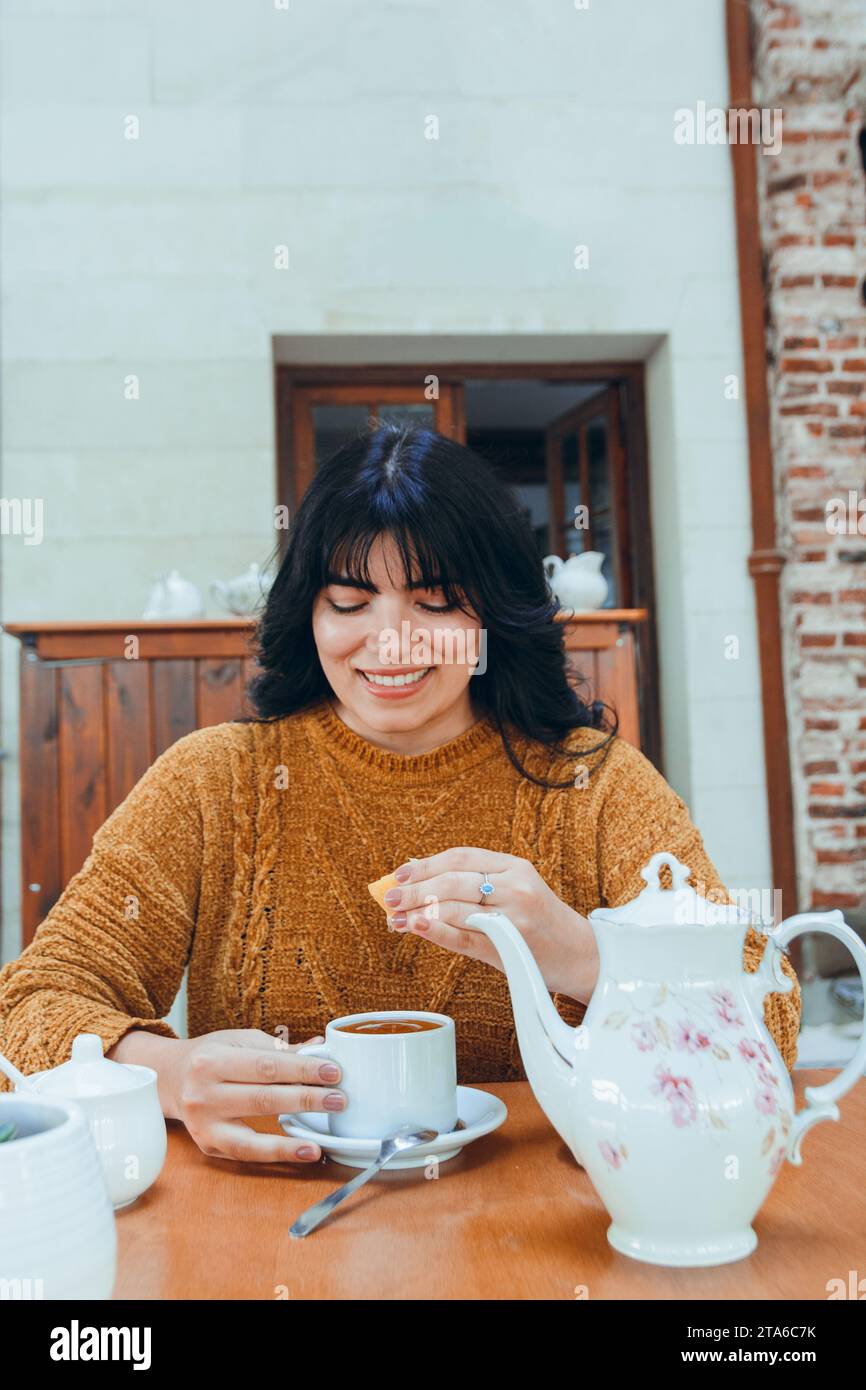 vertical image of happy and smiling young Latin woman, sitting in ...