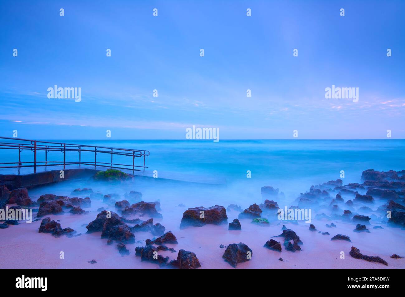 Mettams Pool at dusk with rocks, disability access ramp and misty ...