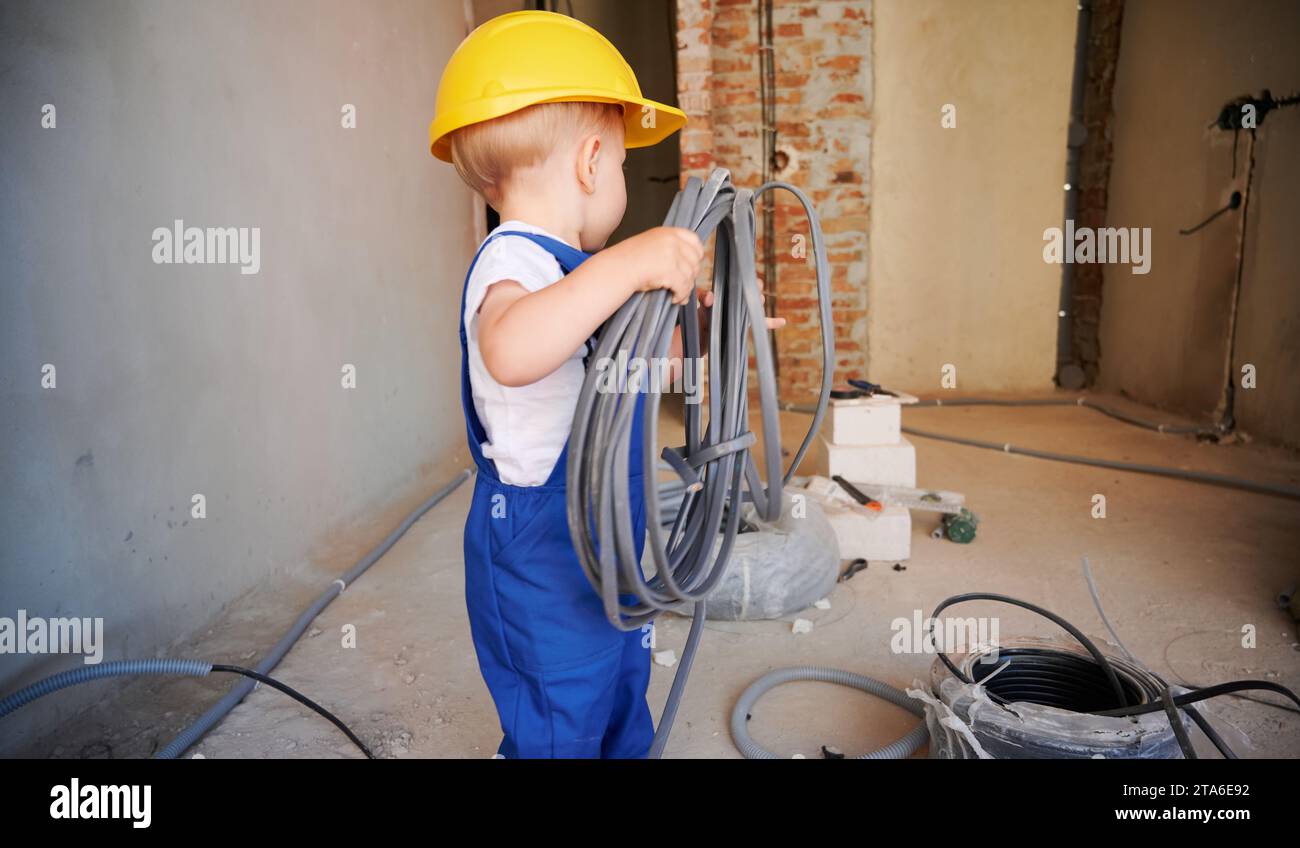Baby boy construction worker holding electrical wires while walking ...