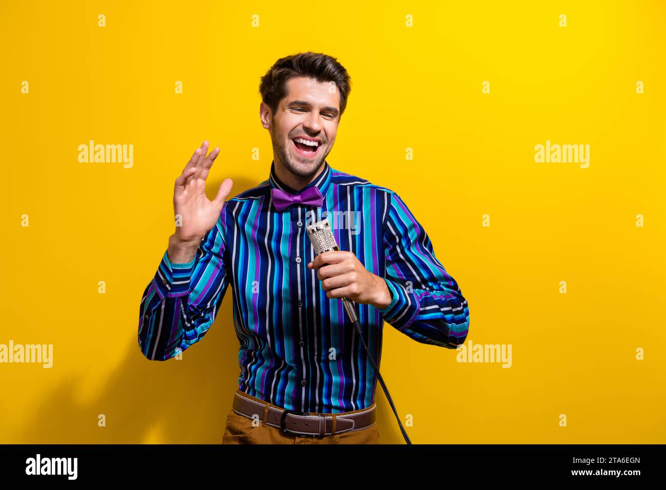 Photo of good mood man dressed striped shirt bow tie holding microphone ...
