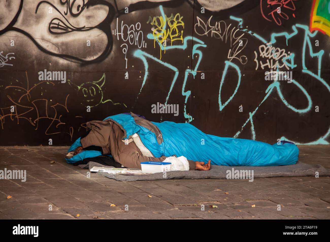 Homeless person laying on the street of Brussels, hungry, powerless ...