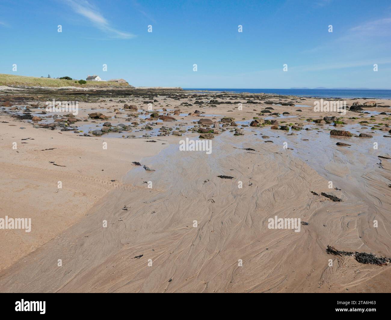 Sandside Bay beach looking toward Fresgoe Harbour buildings in the ...
