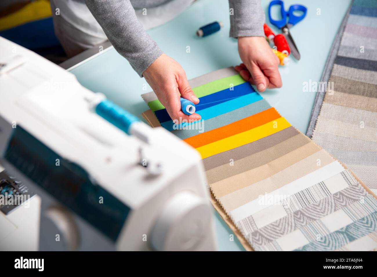 Tailor choosing right color of a blue thread using fabric samples on ...
