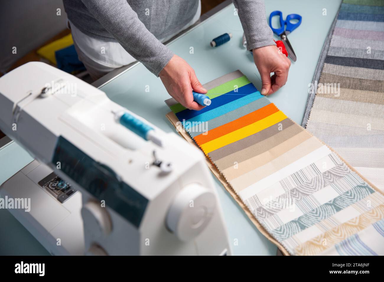 Tailor choosing right color of a blue thread using fabric samples on ...