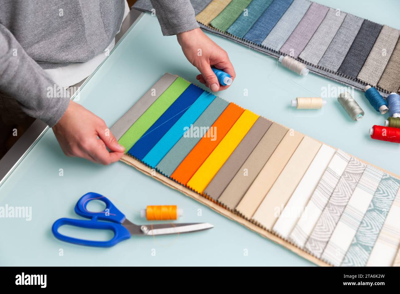 Tailor choosing right color of a blue thread using fabric samples on ...