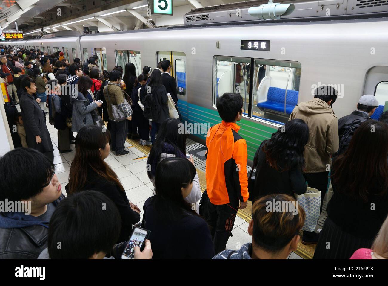 TOKYO, JAPAN - DECEMBER 3, 2016: Passengers wait in line to board local ...