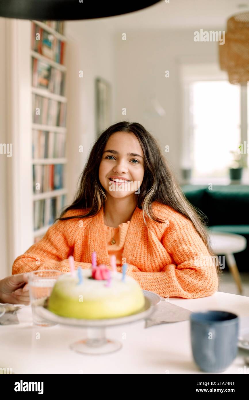 Portrait of happy girl sitting with birthday cake at dining table Stock ...