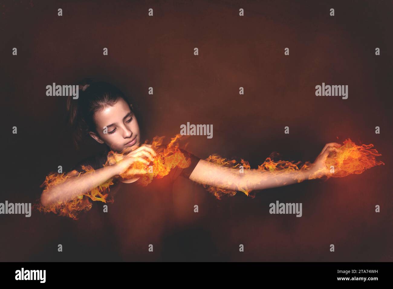 Portrait of a teenage girl doing a magic trick setting her arms on fire ...