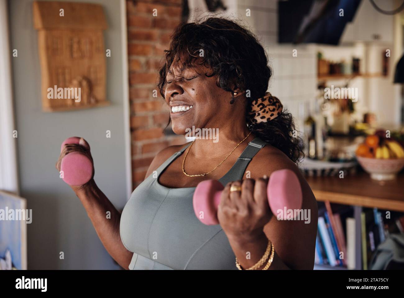Mature woman with eyes closed clenching teeth while exercising with ...
