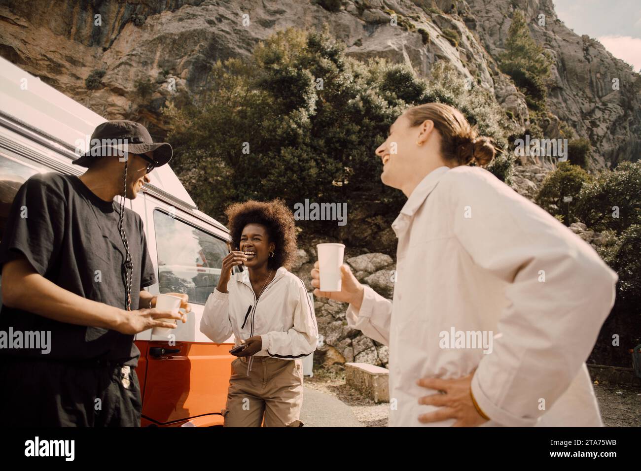 Happy multiracial male and female friends talking while having drinks ...