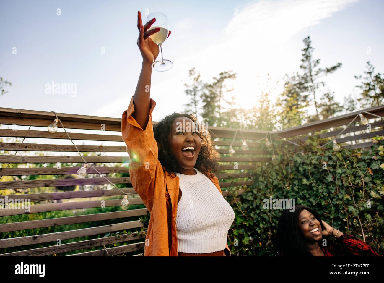 Excited young woman screaming while celebrating during dinner party ...