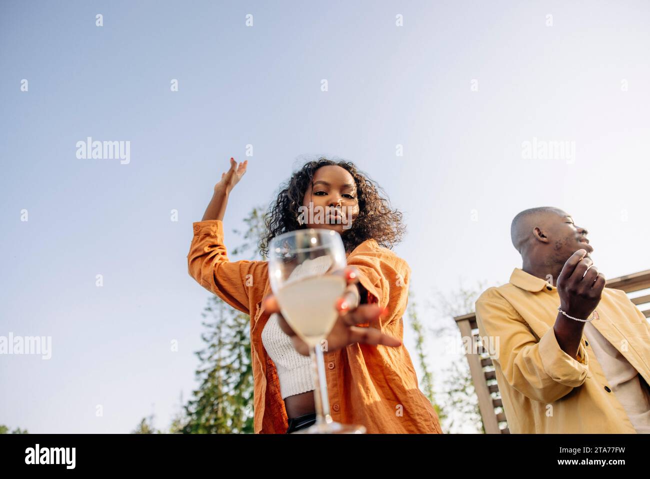 Woman holding drink while dancing with male friend at dinner party ...