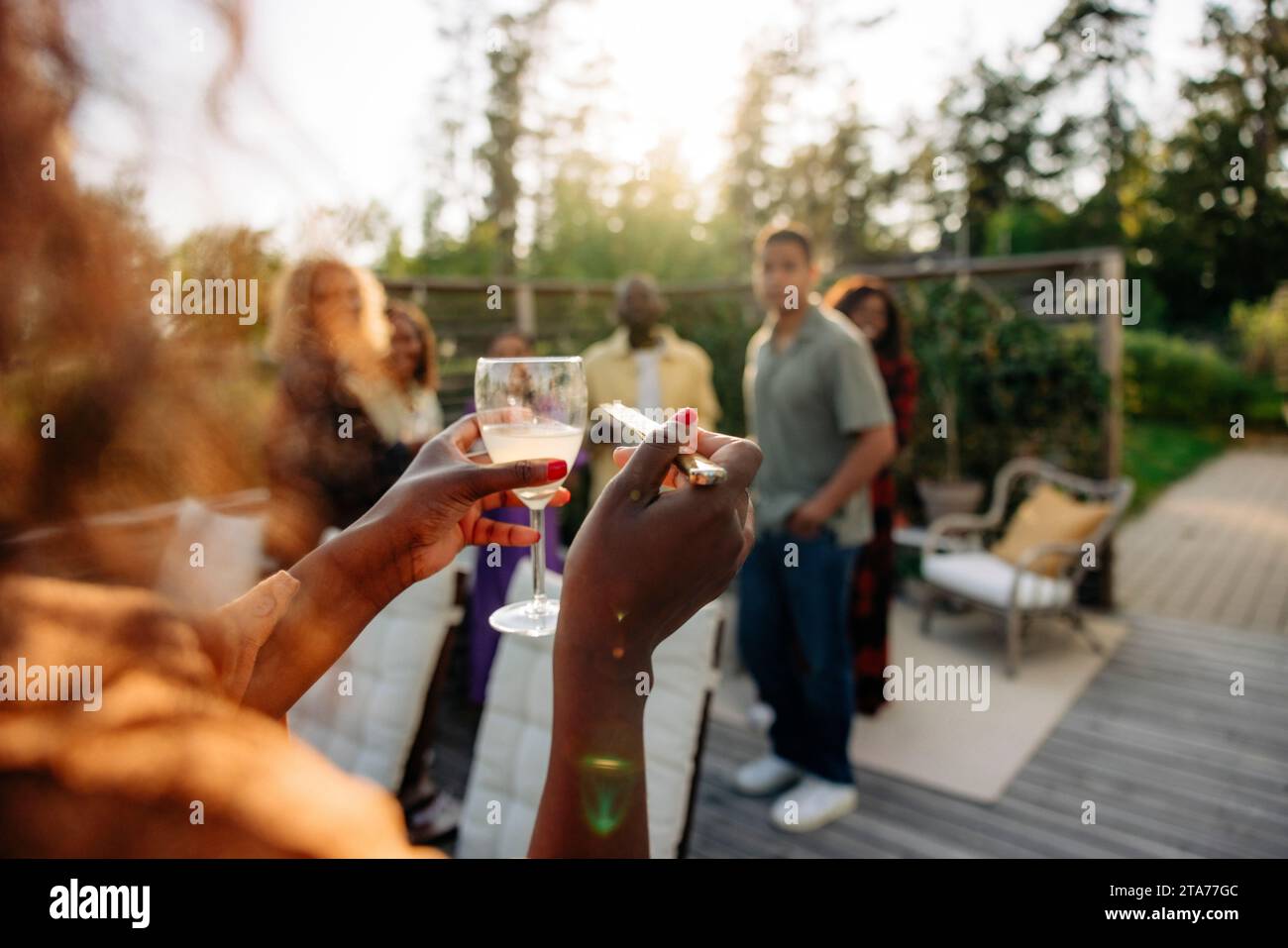 Woman holding drink glass while hosting dinner party with friends in ...