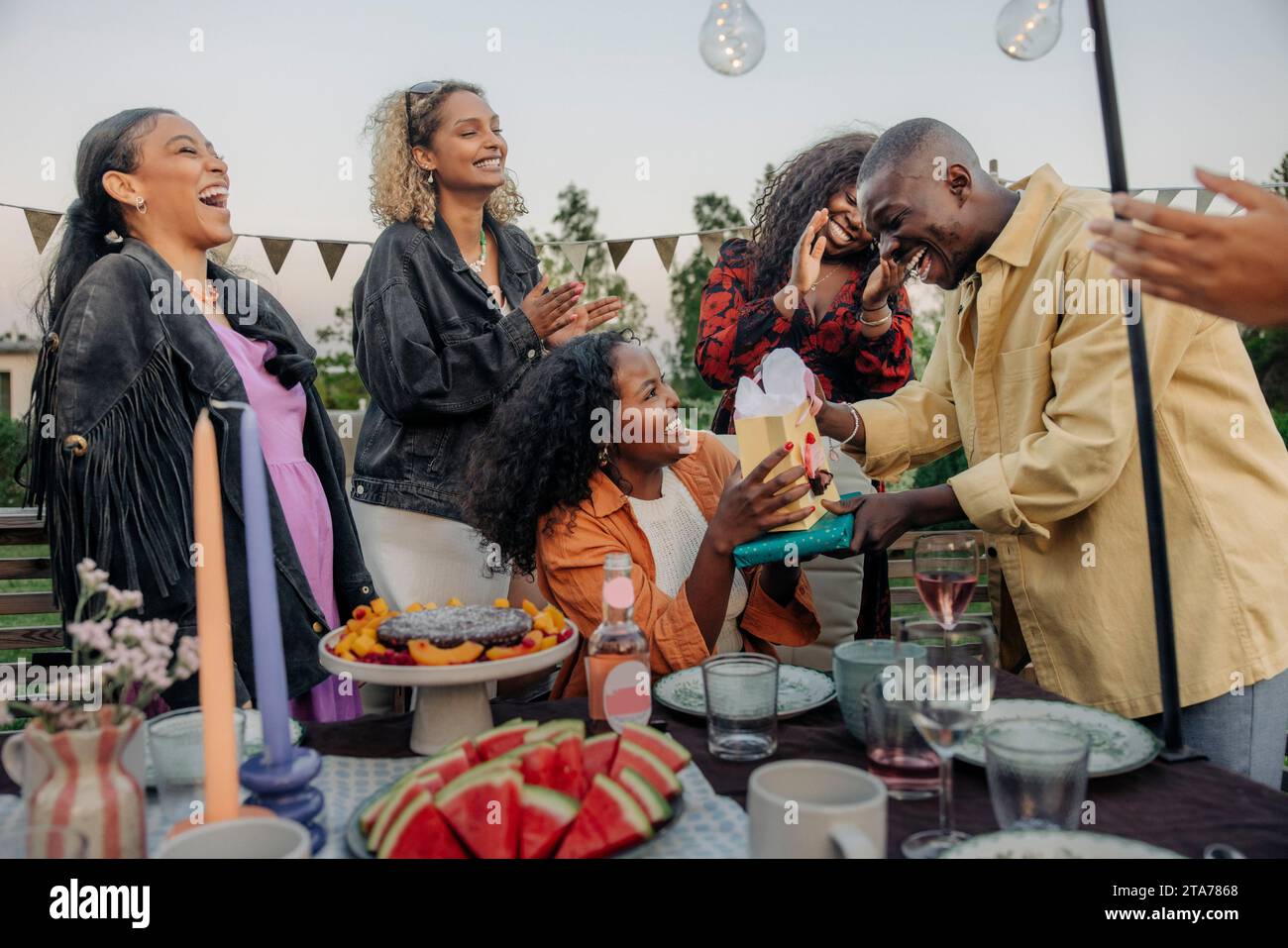 Young man giving gifts to female friend while celebrating birthday in ...