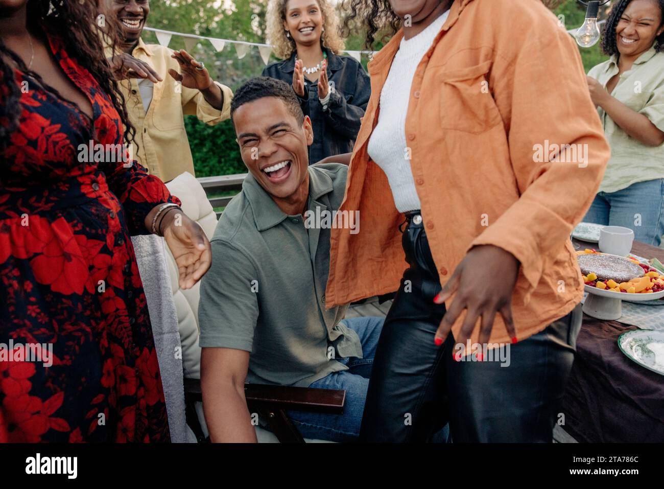Happy man laughing with friends during birthday celebration in back ...