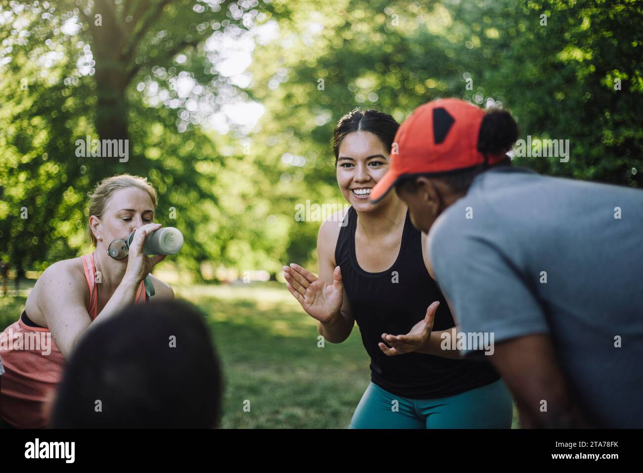 Smiling female coach motivating team during training at park Stock ...