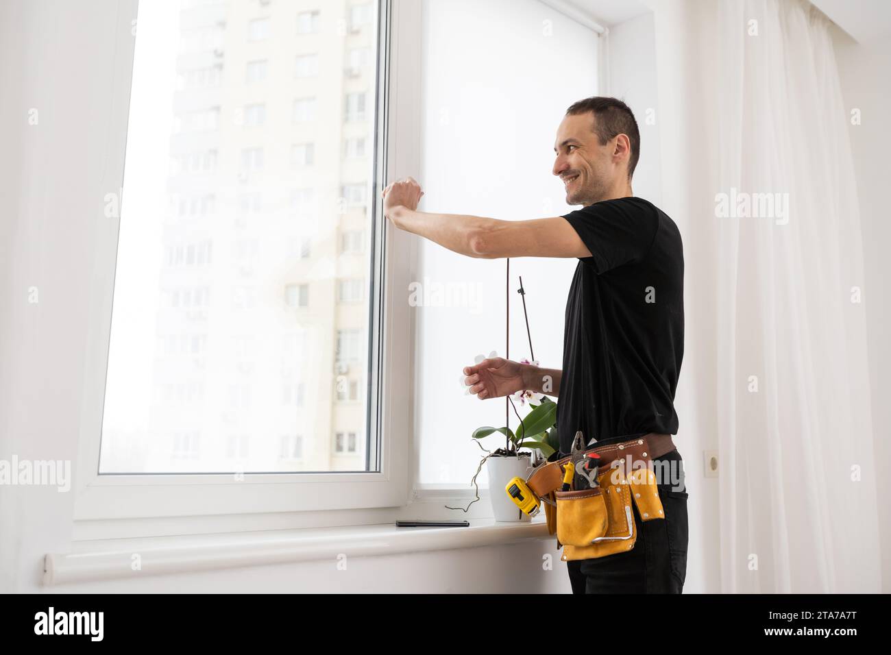 Handyman using a cordless screwdriver to install a window handle ...