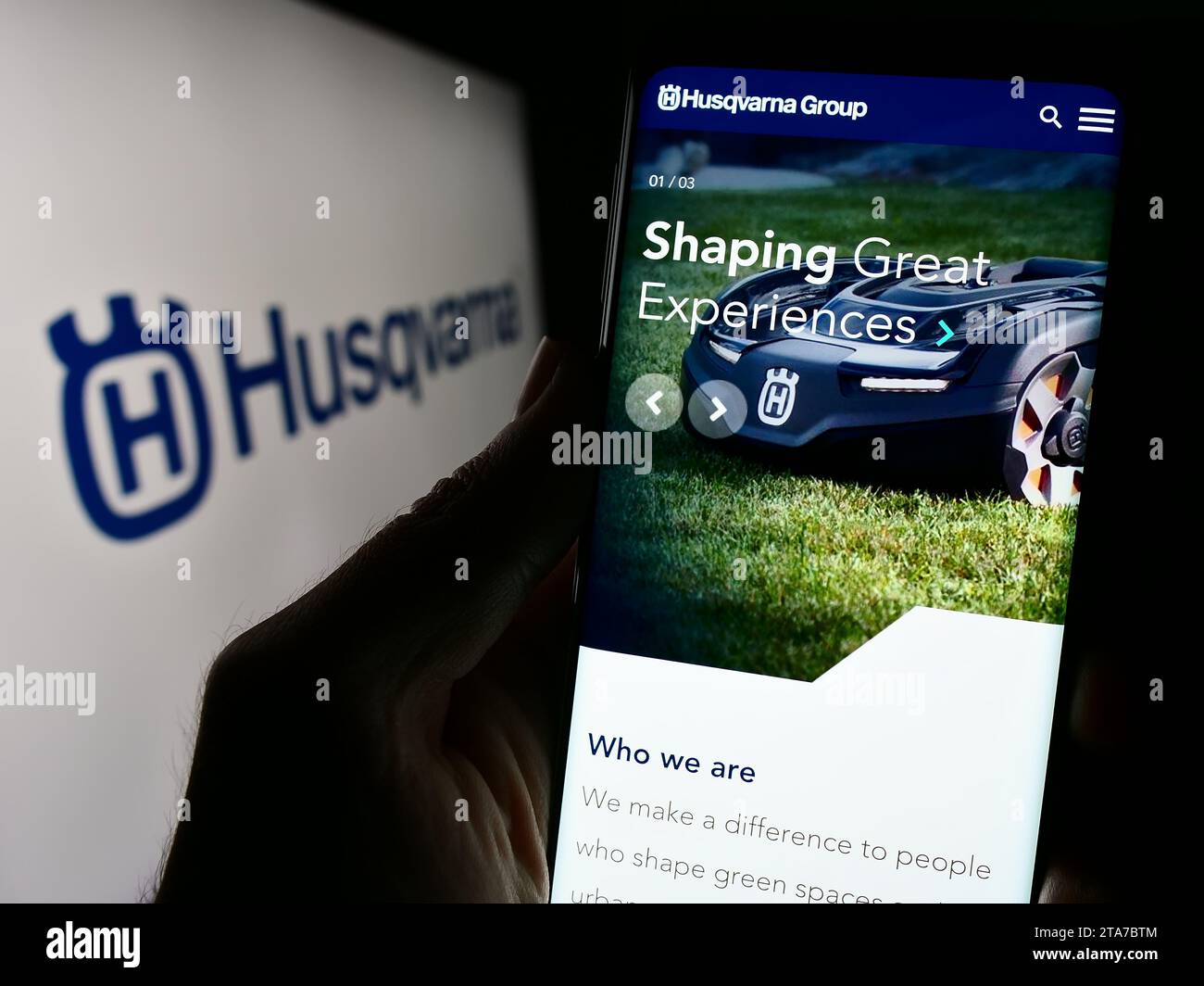Person holding cellphone with webpage of Swedish power products company Husqvarna AB in front of ...