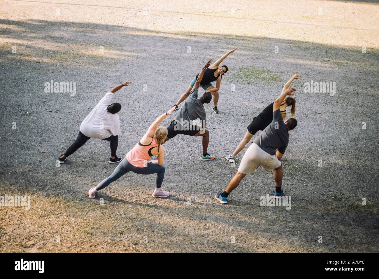 Team doing stretching with female instructor at park Stock Photo - Alamy
