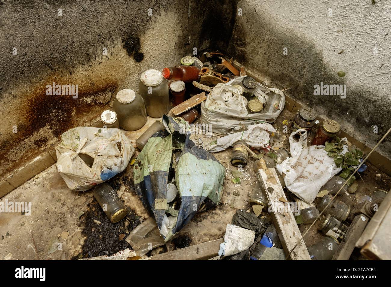 Corner of a room in an abandoned house full of trash, old cans and dirt ...