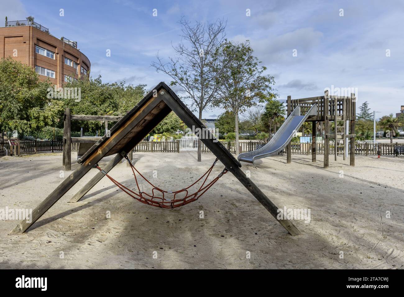 An urban playground with swings and slides and other games on a sandy ...