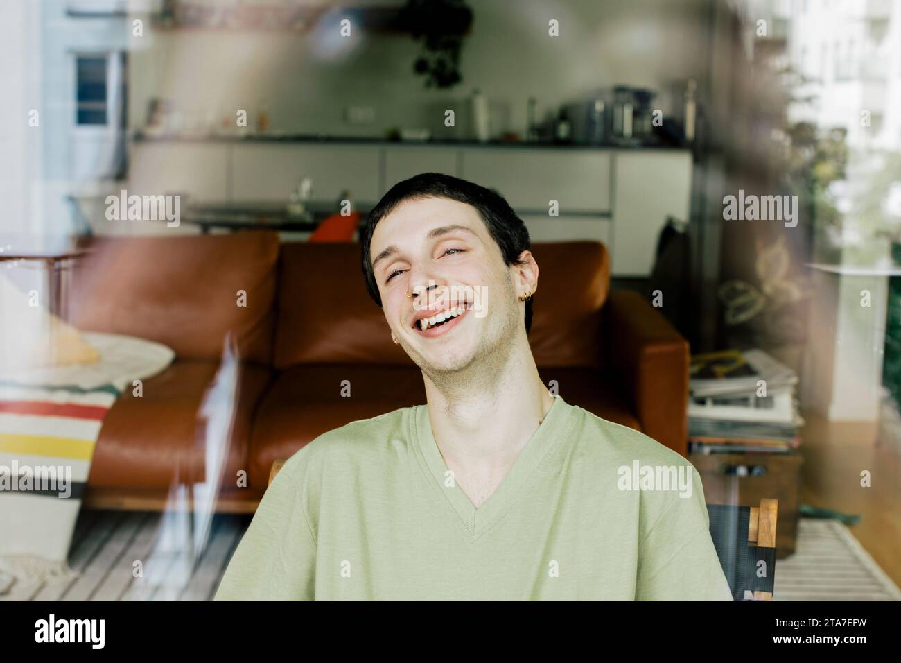 Happy young man enjoying at home seen through glass window Stock Photo ...