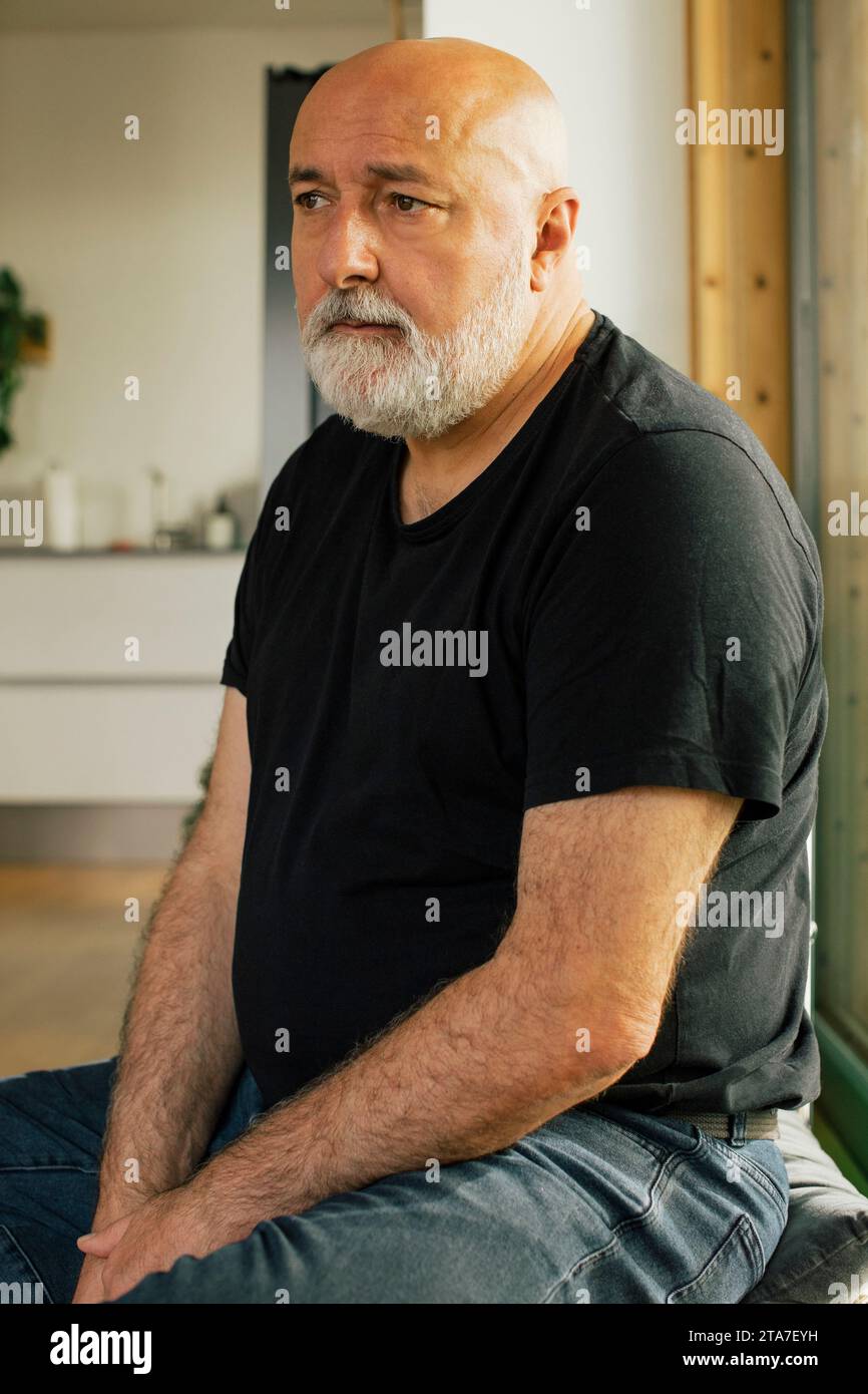Upset mature man with shaved head sitting at home Stock Photo - Alamy