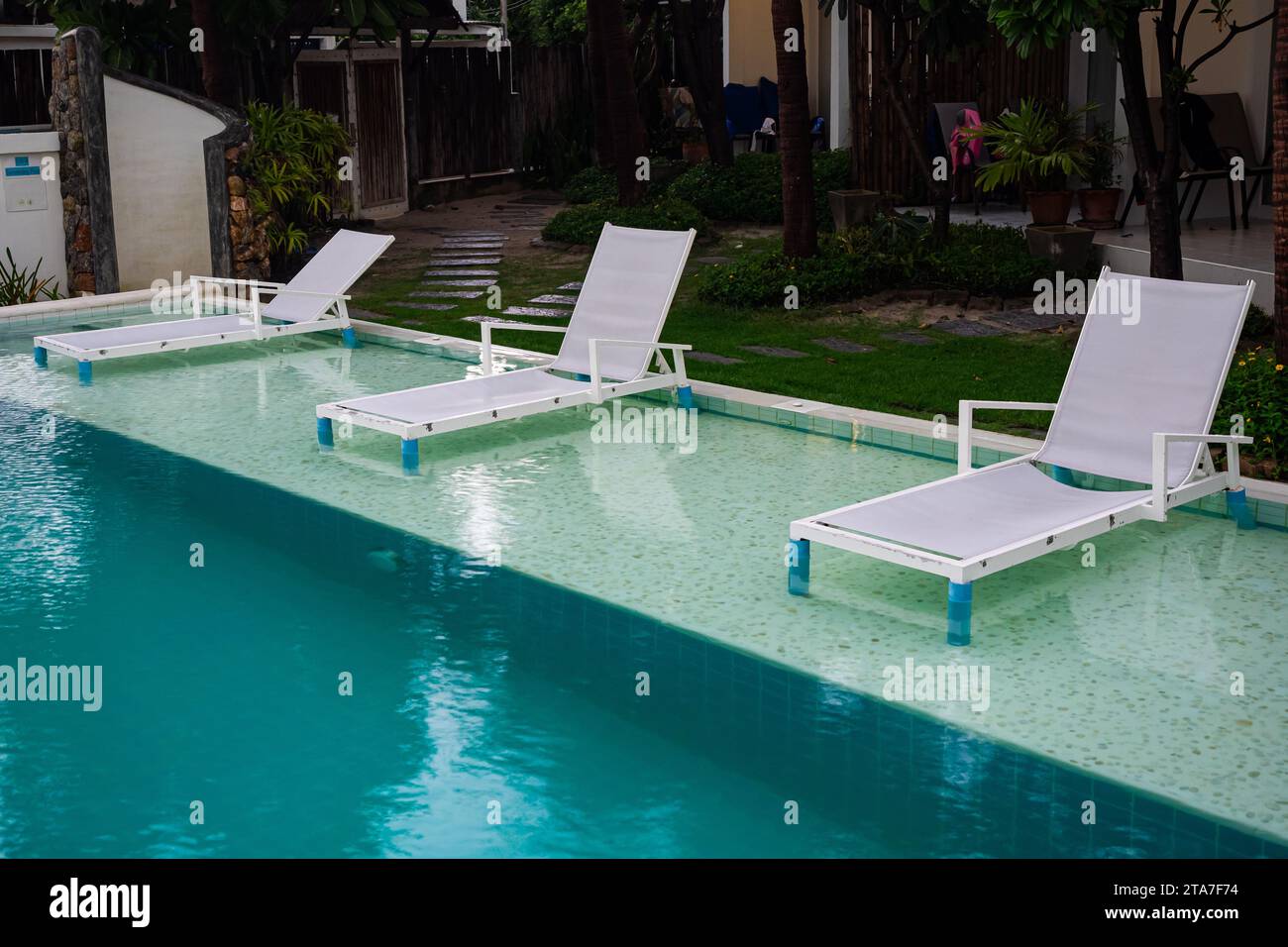 View row of white beach chairs in swimming pool in a resort villa at ...
