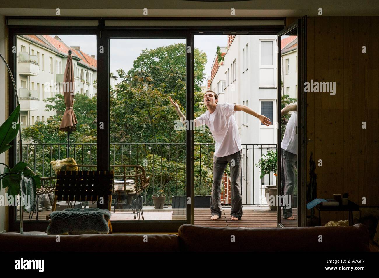 Carefree man dancing in balcony seen through door Stock Photo - Alamy