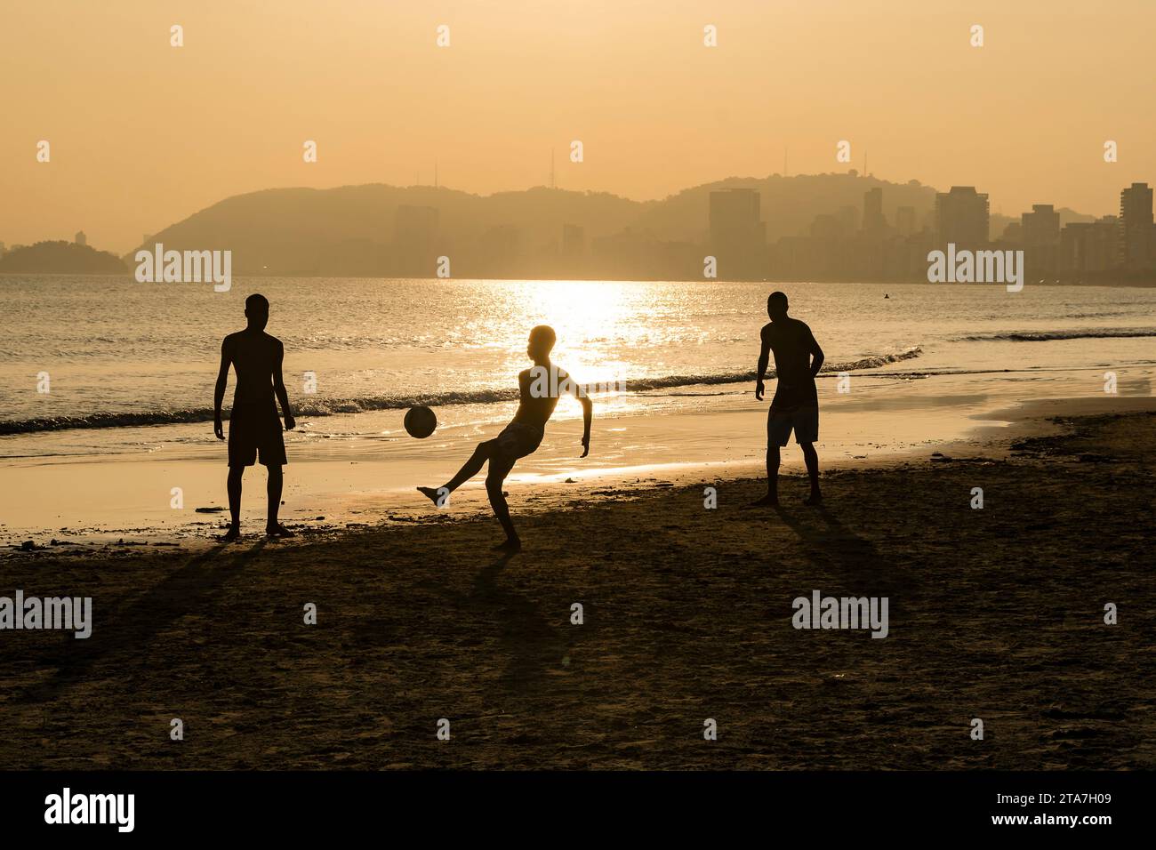 Santos city, Brazil. Brazilian boys playing football on the beach next ...